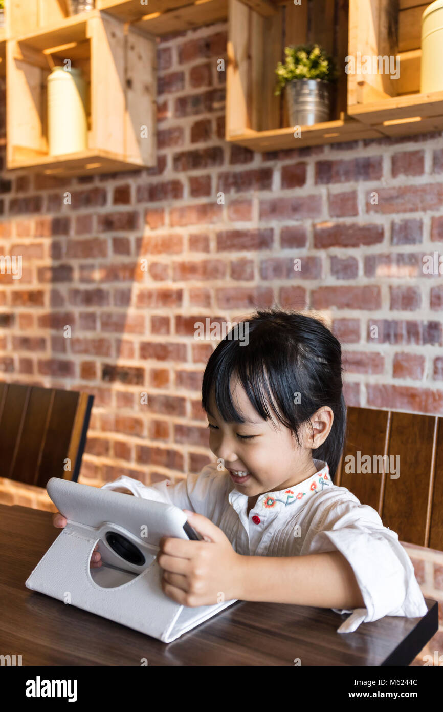 Asian Chinese little girl playing tablet computer at indoor cafe Stock ...
