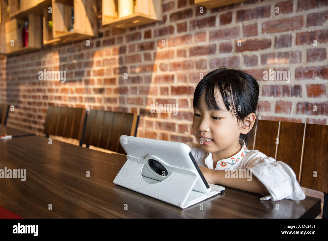 Asian Chinese little girl playing tablet computer at indoor cafe Stock ...