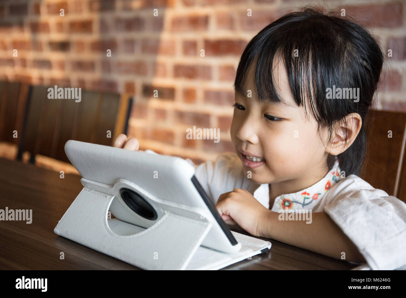 Asian Chinese little girl playing tablet computer at indoor cafe Stock ...