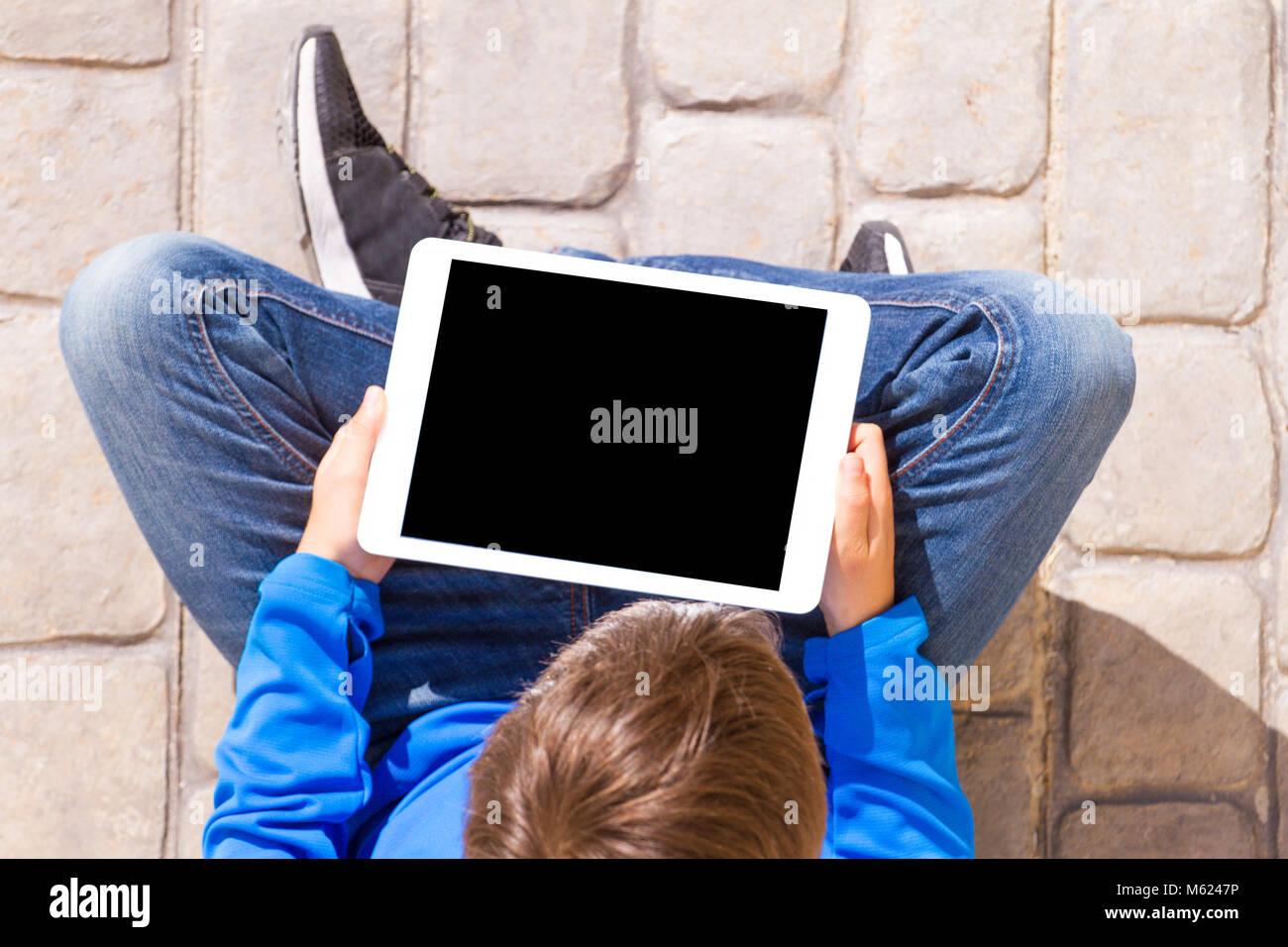 Tablet computer in the hands of a child who sitting on the ground Stock ...