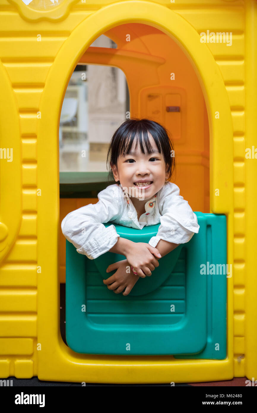 Asian Chinese little girl playing in toy house at indoor playground ...