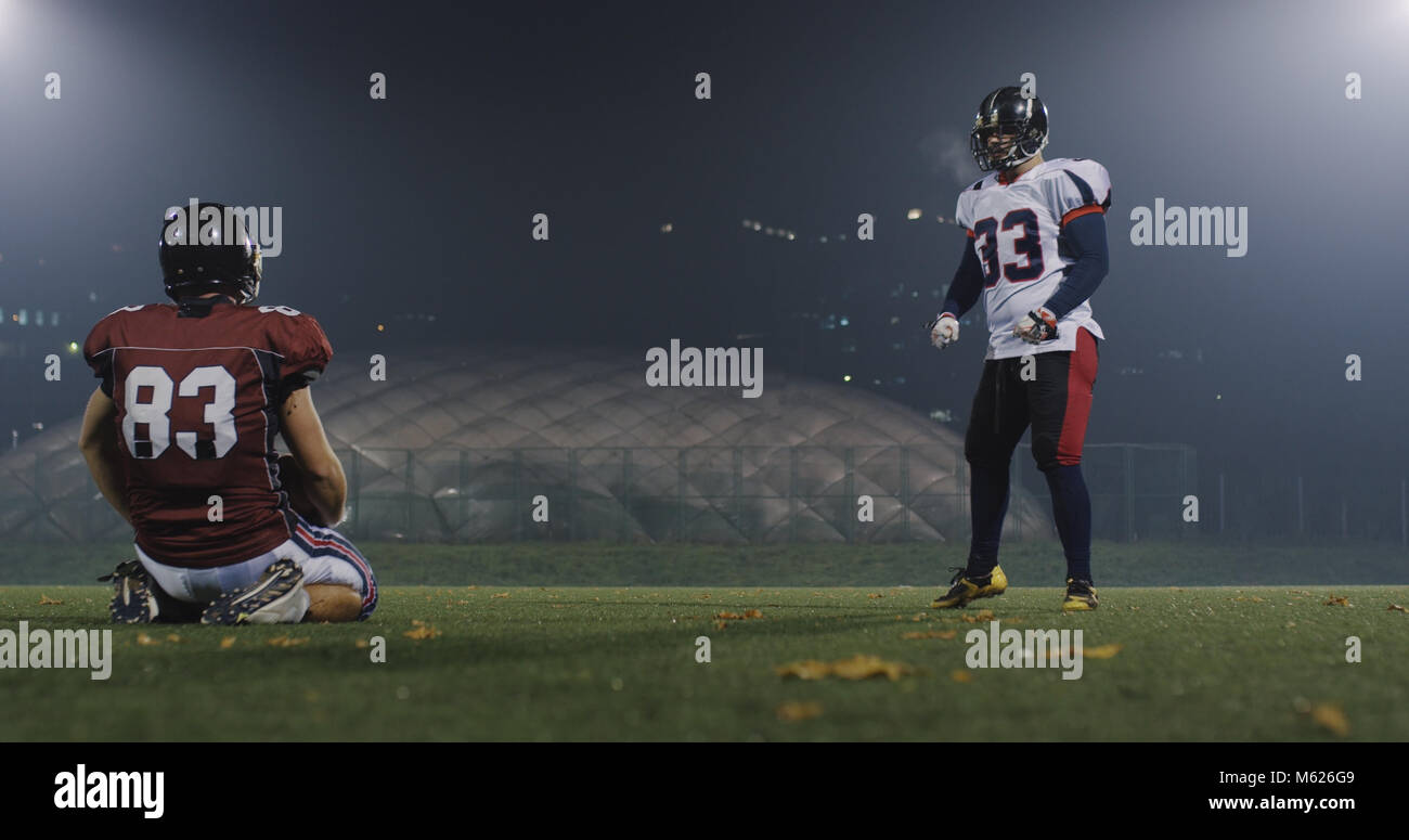 American football players in action at night game time on the field ...