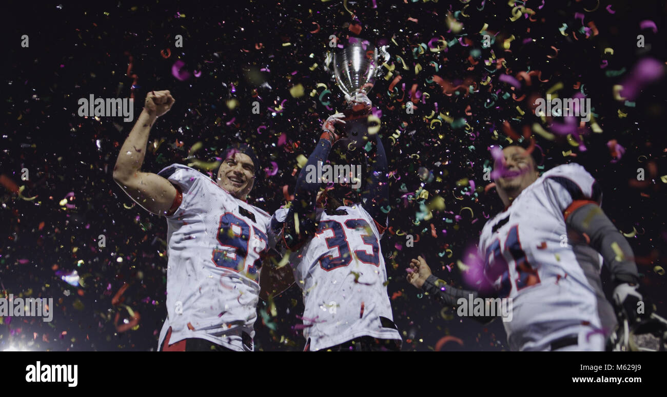 happy american football team celebrating victory with trophy and ...