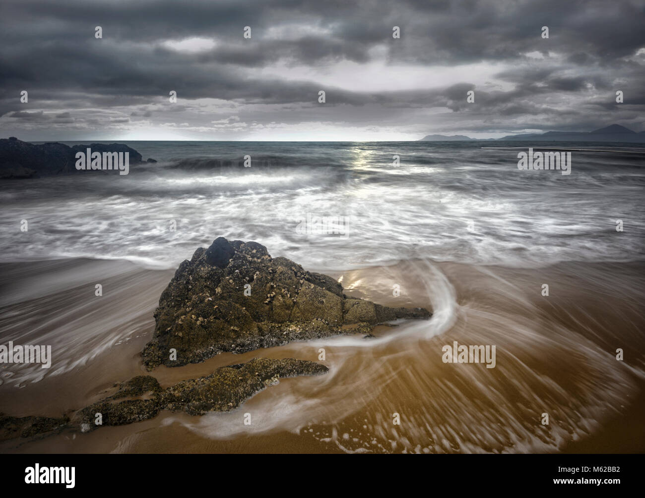 Waves motion blur around a rock at Yorkeys Knob Beach during a storm ...