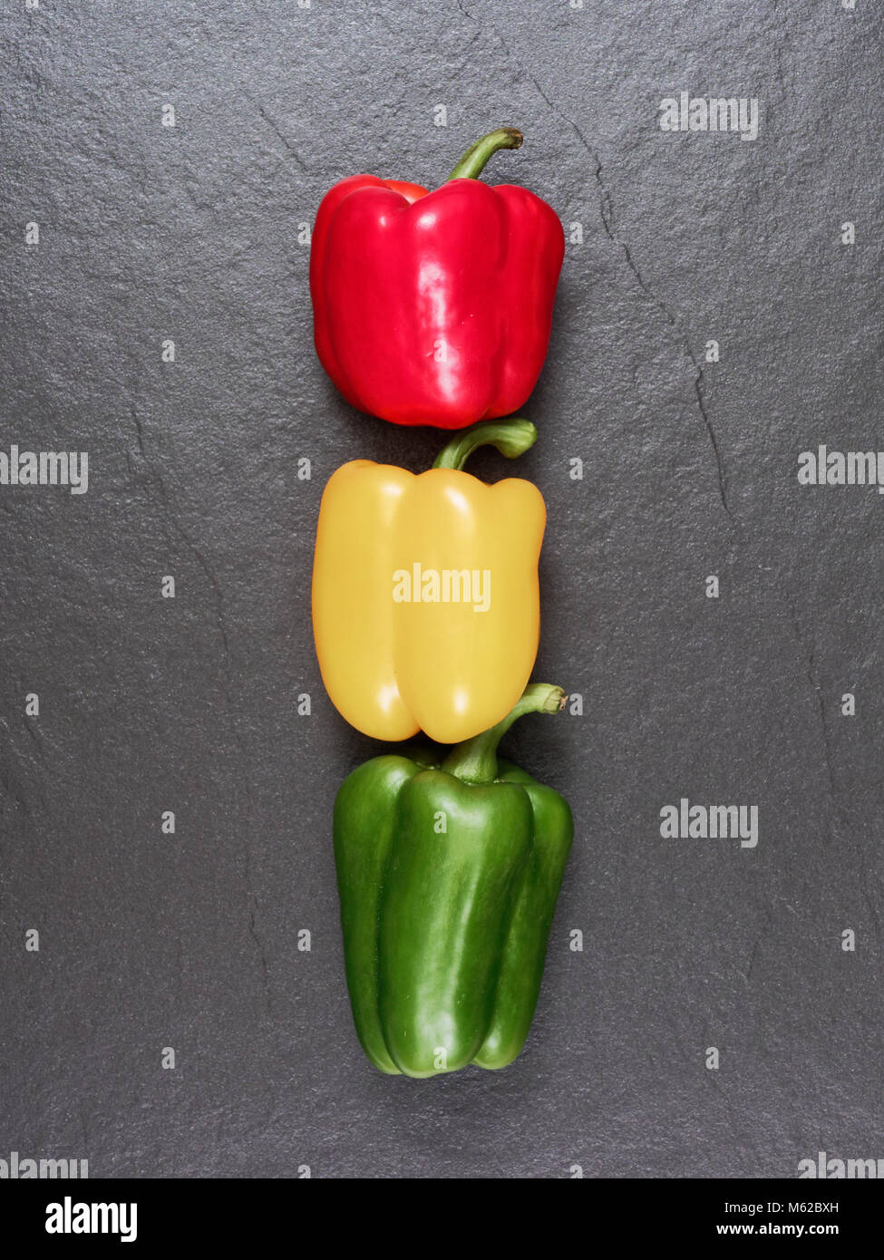 Red, yellow, and green bell pepper or capsicum put together vertically ...