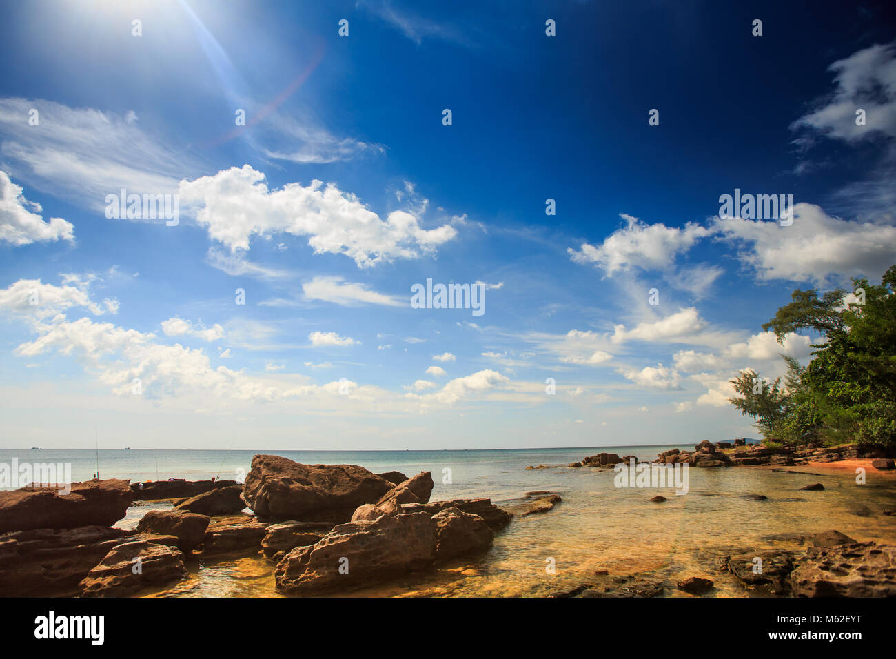 flat transparent yellow stony sea bottom under low tide against azure ...