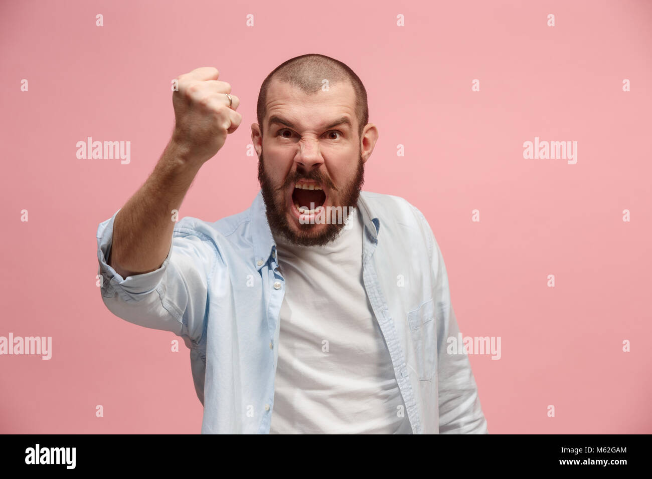 The young emotional angry man screaming on pink studio background Stock ...
