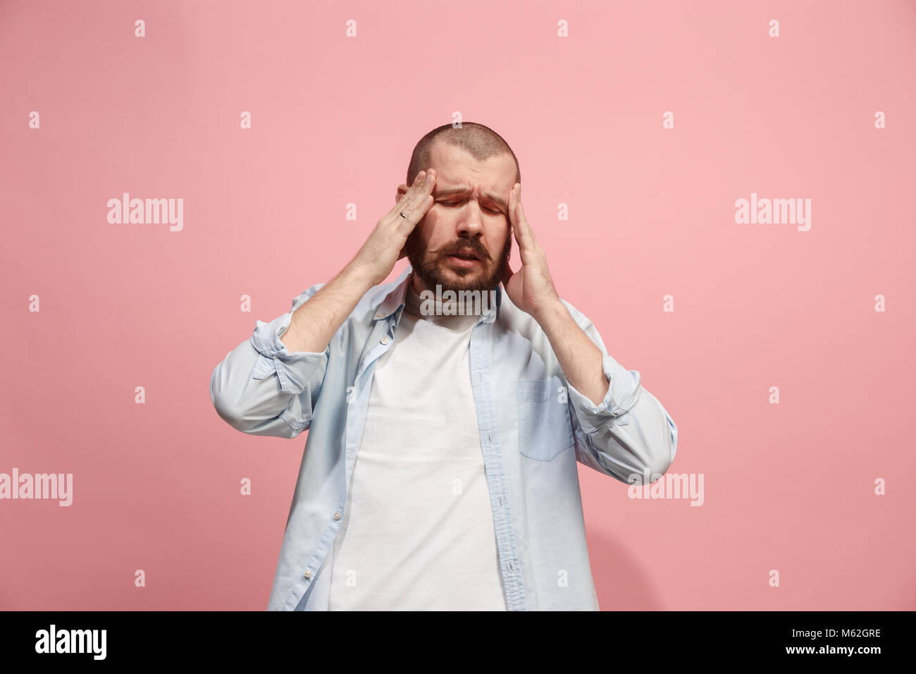 Man having headache. Isolated over pink background Stock Photo - Alamy