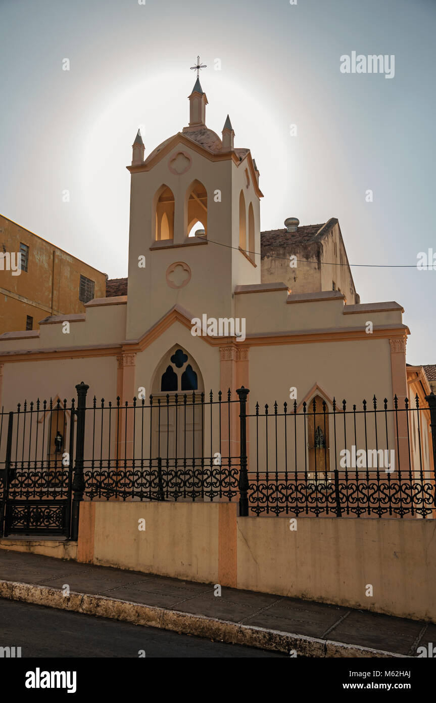 Facade of small church and belfry, behind iron fence, with sunshine ...