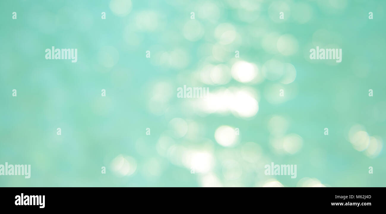 Soft focus bokeh light effects over a rippled, blue water background in ...