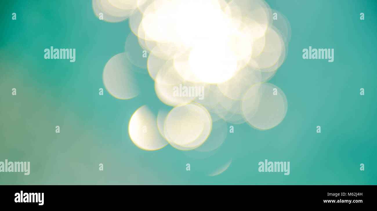 Soft focus bokeh light effects over a rippled, blue water background in ...