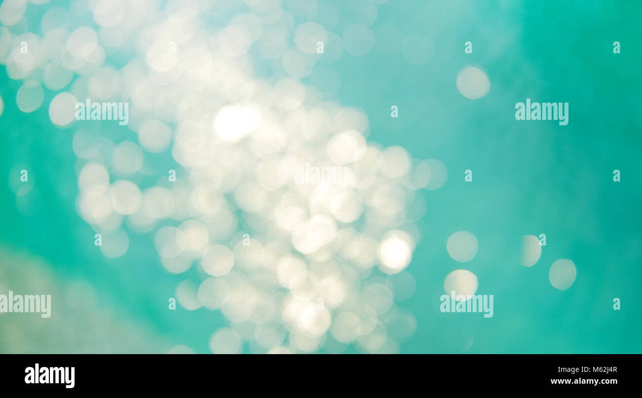 Soft focus bokeh light effects over a rippled, blue water background in ...