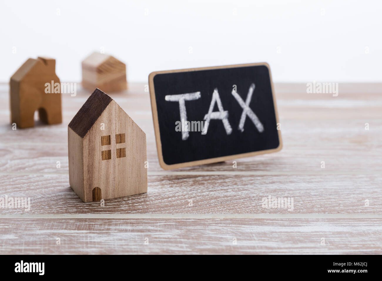 Different model of houses on wooden table with tax sign for property ...