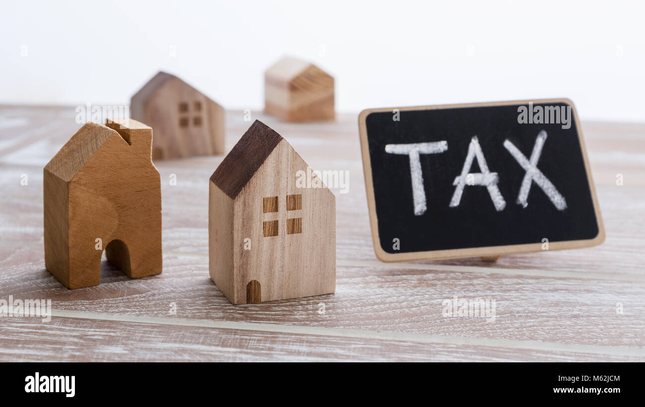 Property tax concept with model of houses with tax sign on wooden table ...