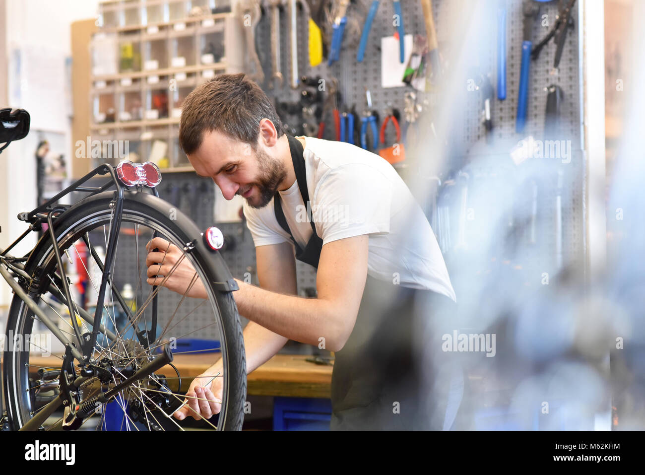 friendly and competent bicycle mechanic in a workshop repairs a bike ...