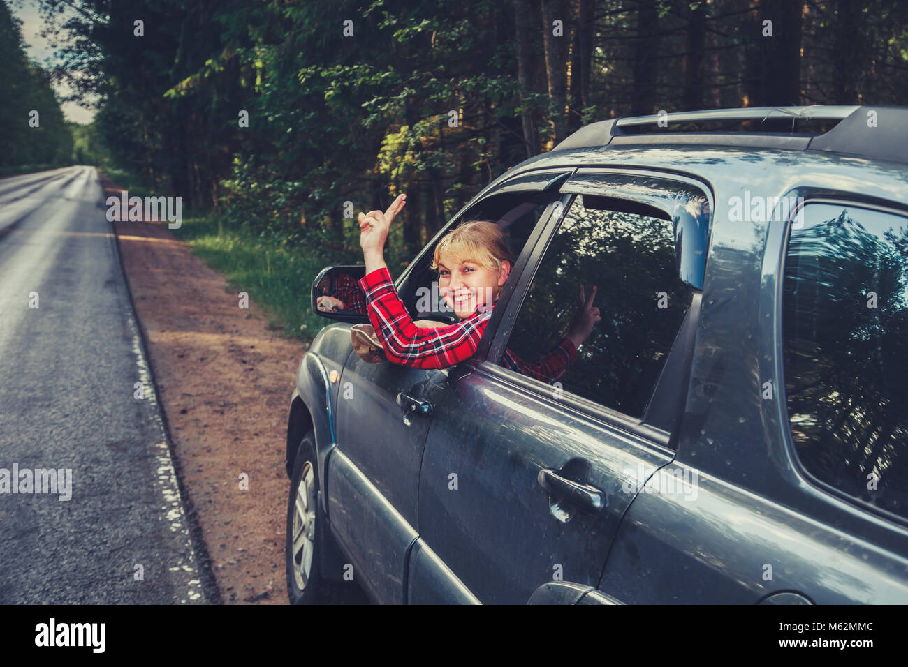 Smiling attractive girl driving a car. Journey through the forest ...