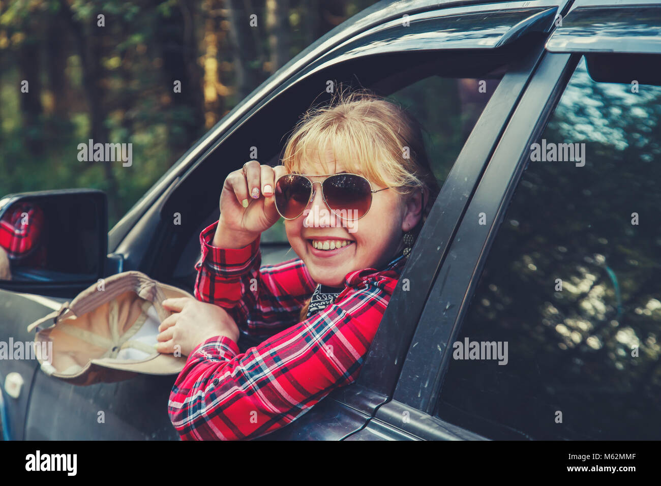 Smiling attractive girl driving a car. Journey through the forest ...