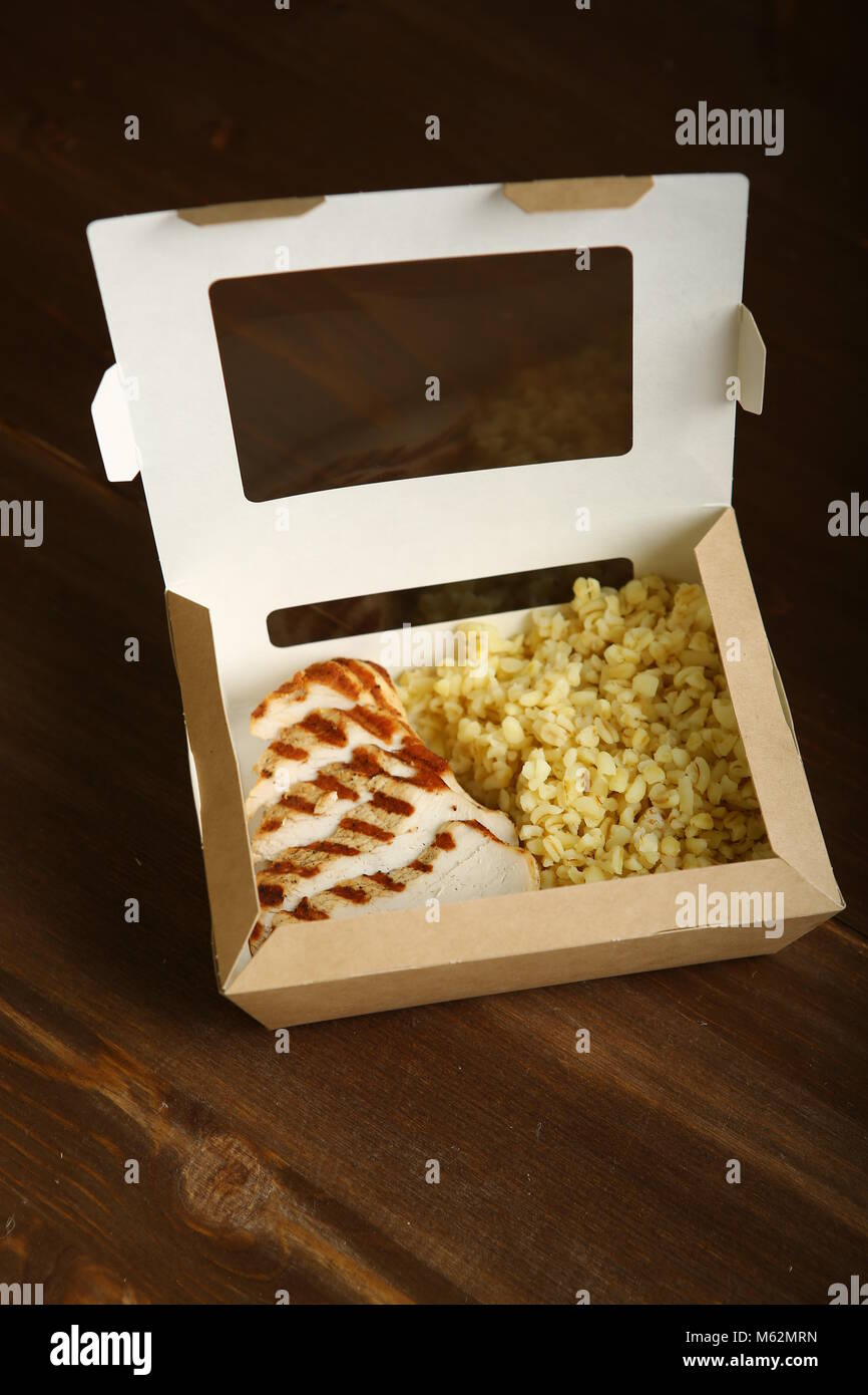 Grilled chicken with slices, with bulgur in a paper container. Delivery ...