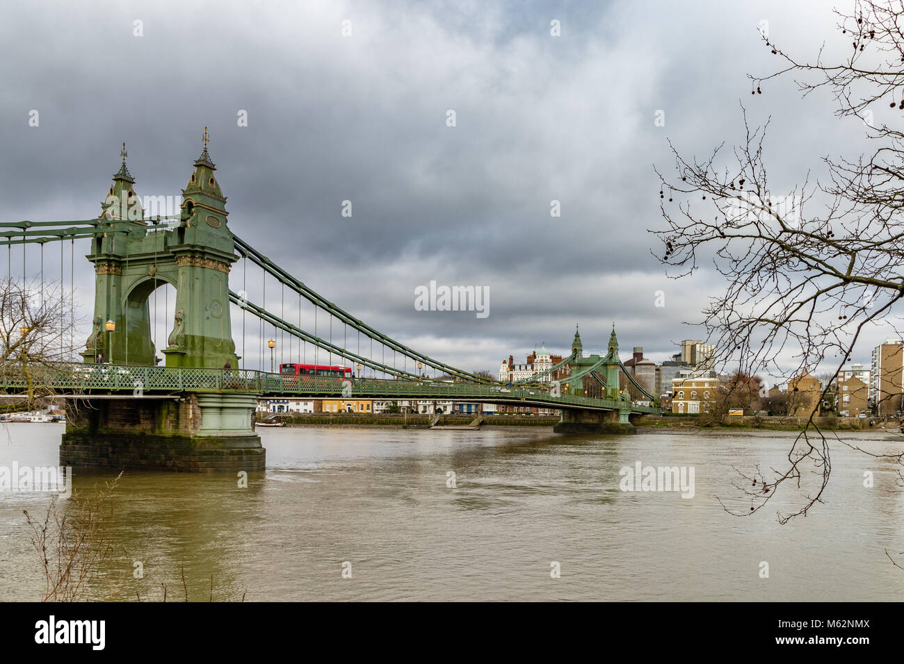 A single decker London Bus crosses Hammersmith Bridge over The River ...