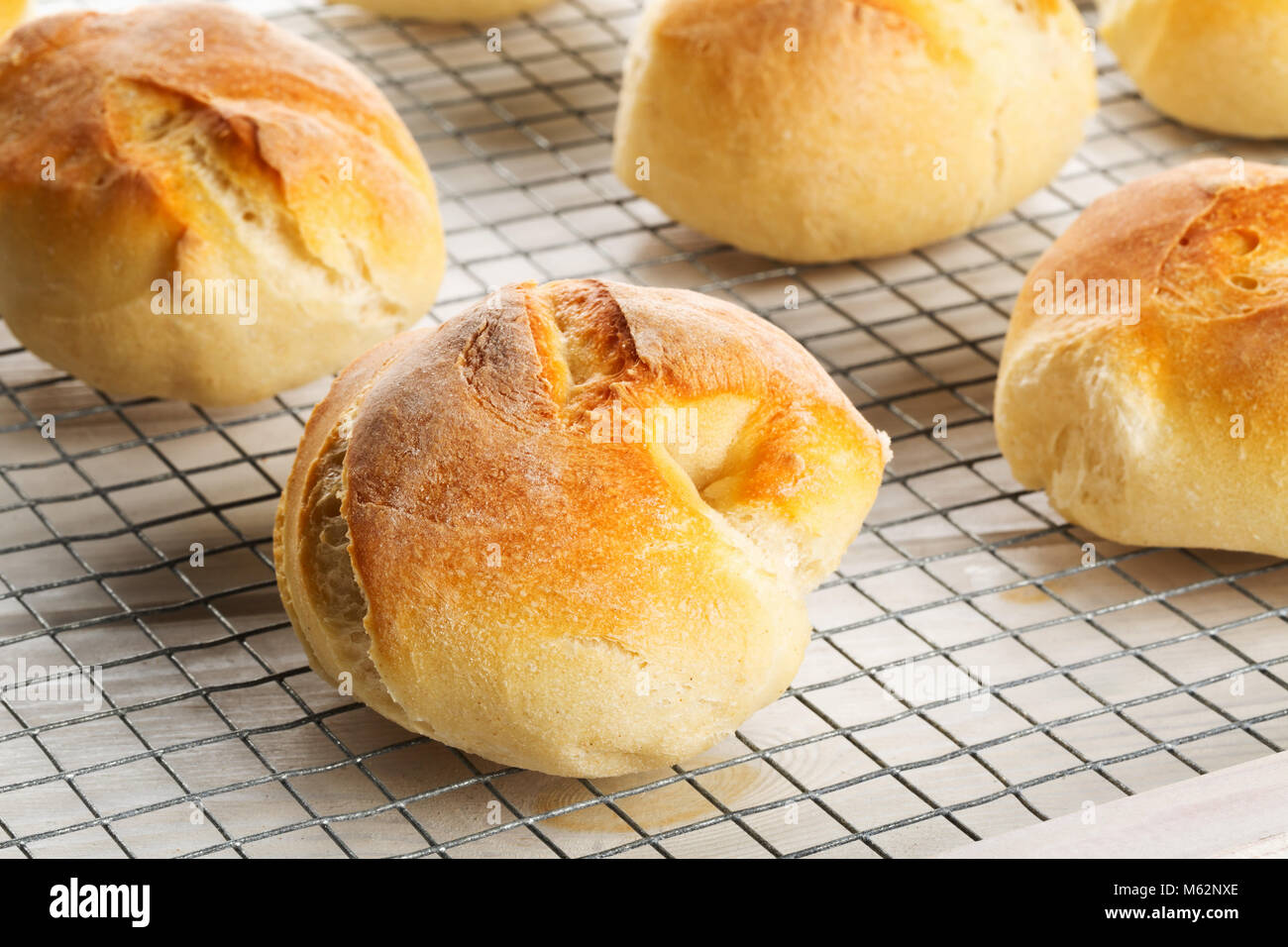 Bunch of whole, fresh baked wheat buns on cooling rack on white wooden ...