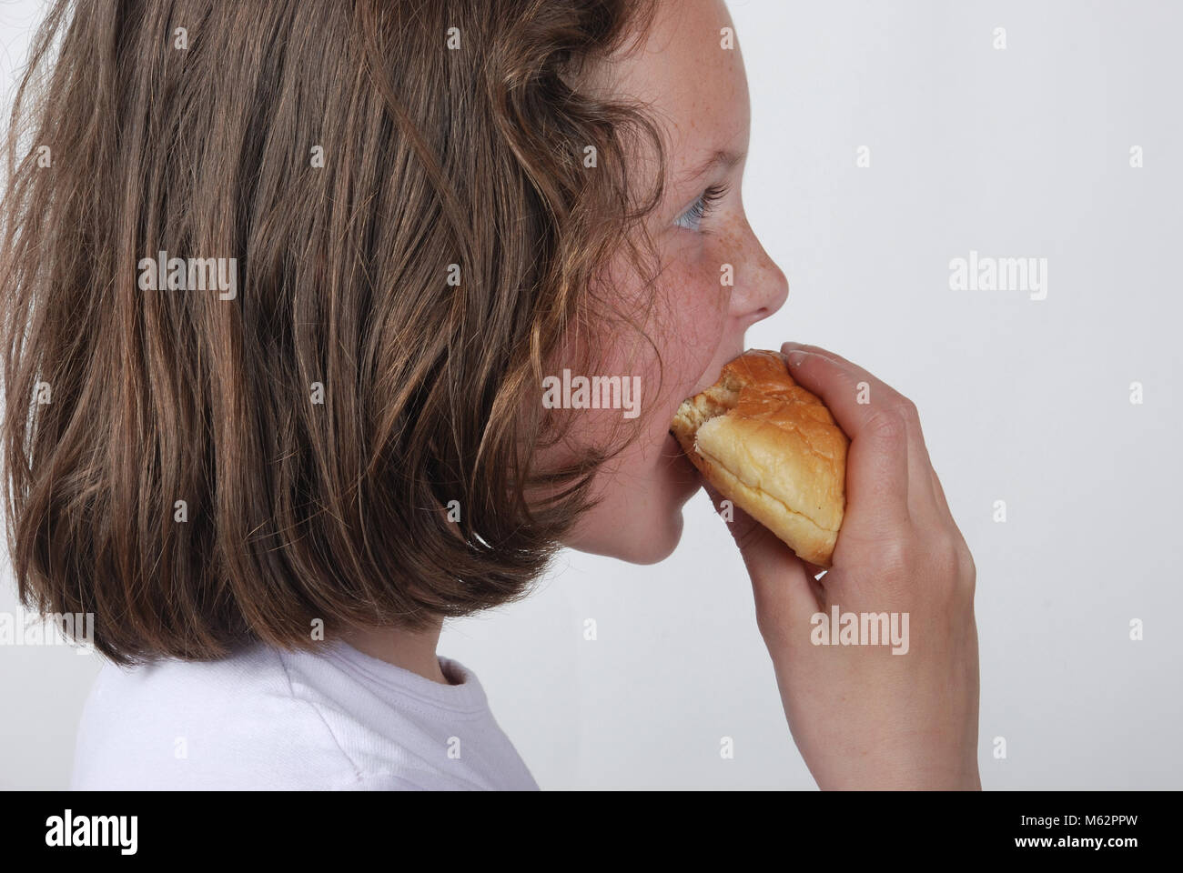 A young girl eating a bun Stock Photo - Alamy