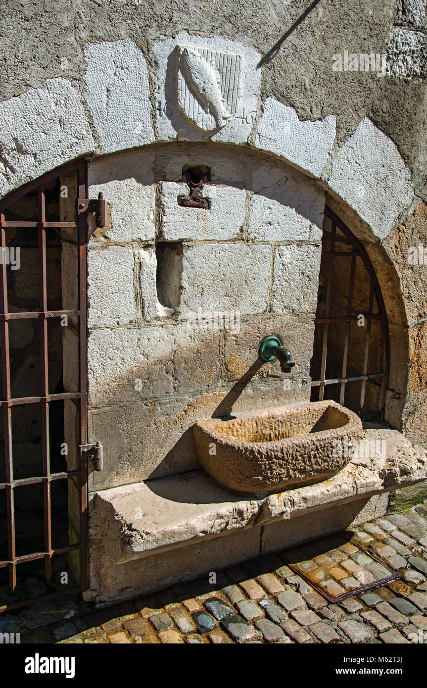 Old stone water fountain with iron gates and heraldic shield on the ...