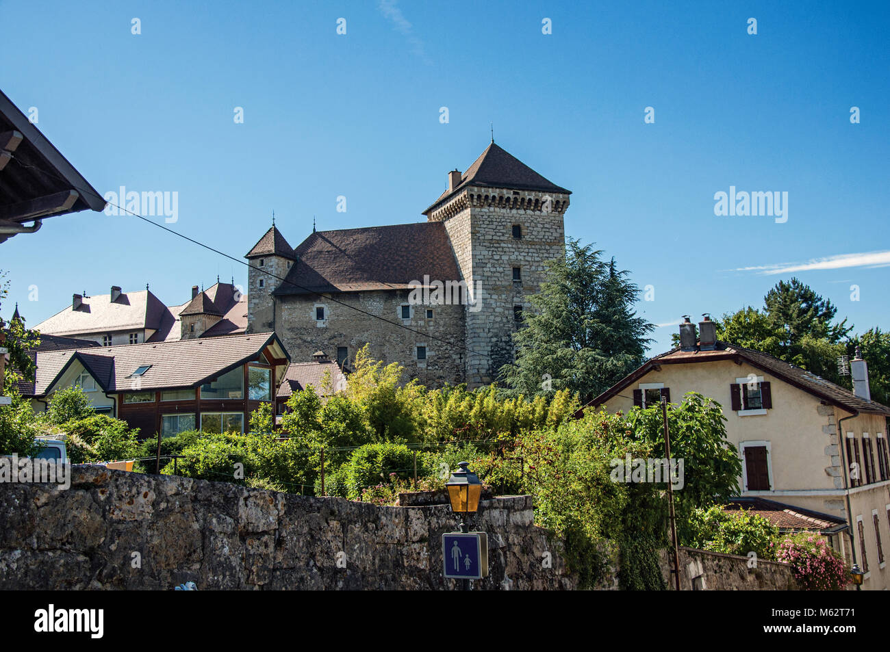 View of Annecy castle and houses with a wall in foreground and blue sky ...