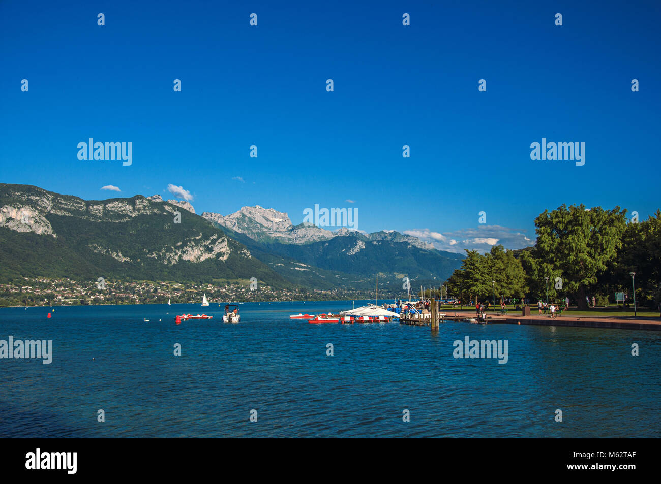 View of Annecy lake, with island, vegetation, paddle boats, mountains ...