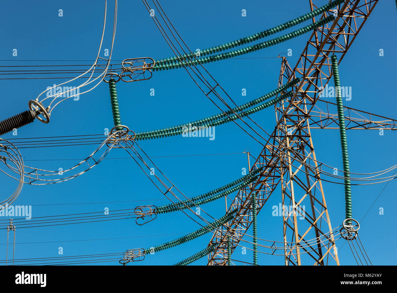 High voltage electrical power lines and isolators against a blue sky ...