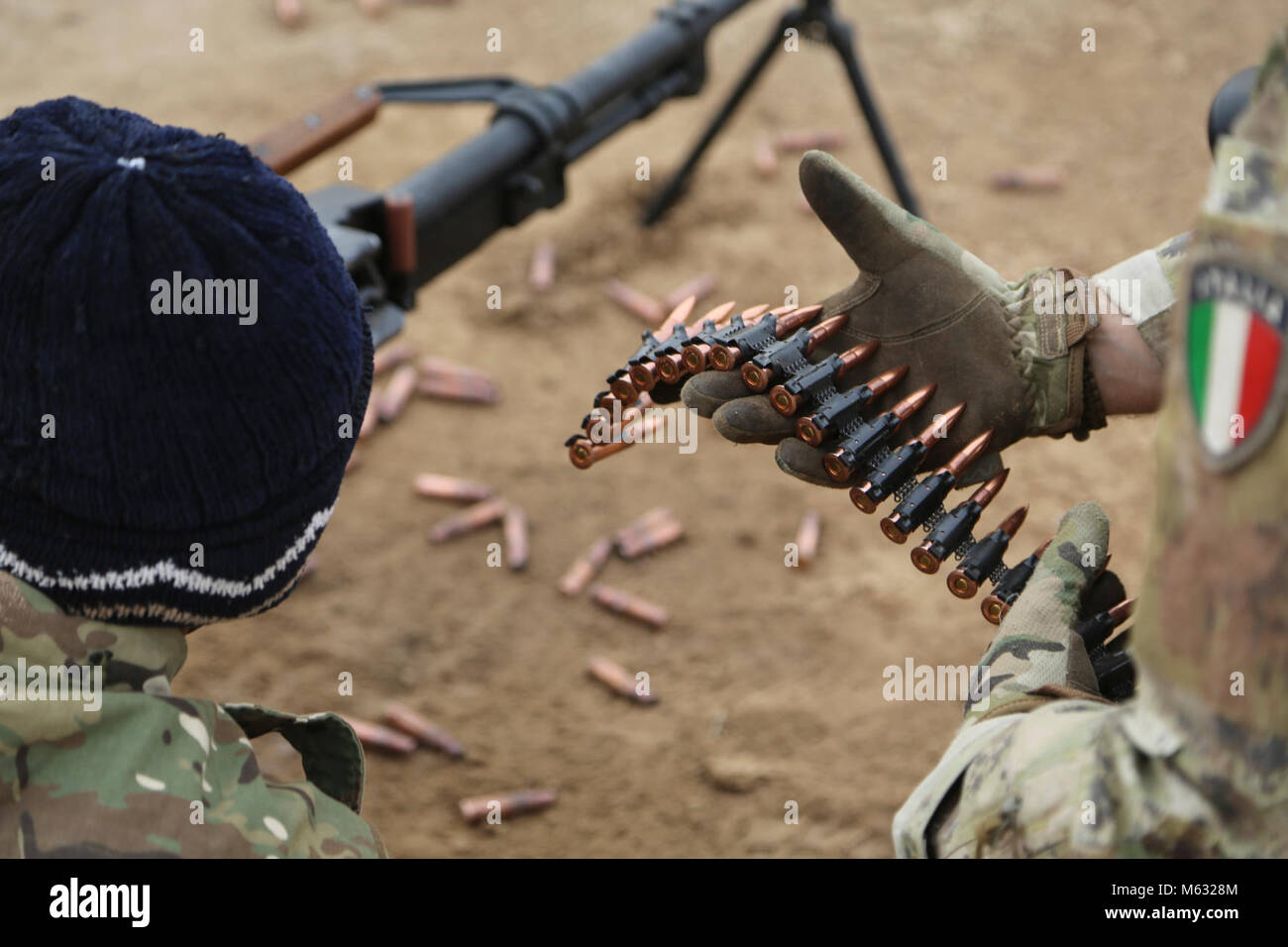 An Italian coalition member hands an Iraqi soldier a belt of ammunition ...