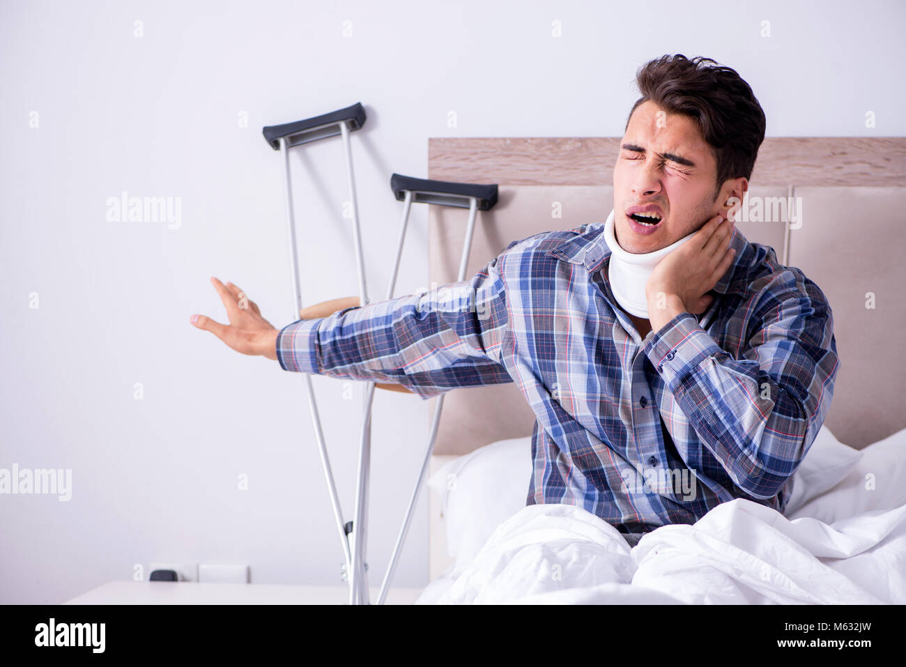 Injured man in bed at home with crutches Stock Photo - Alamy