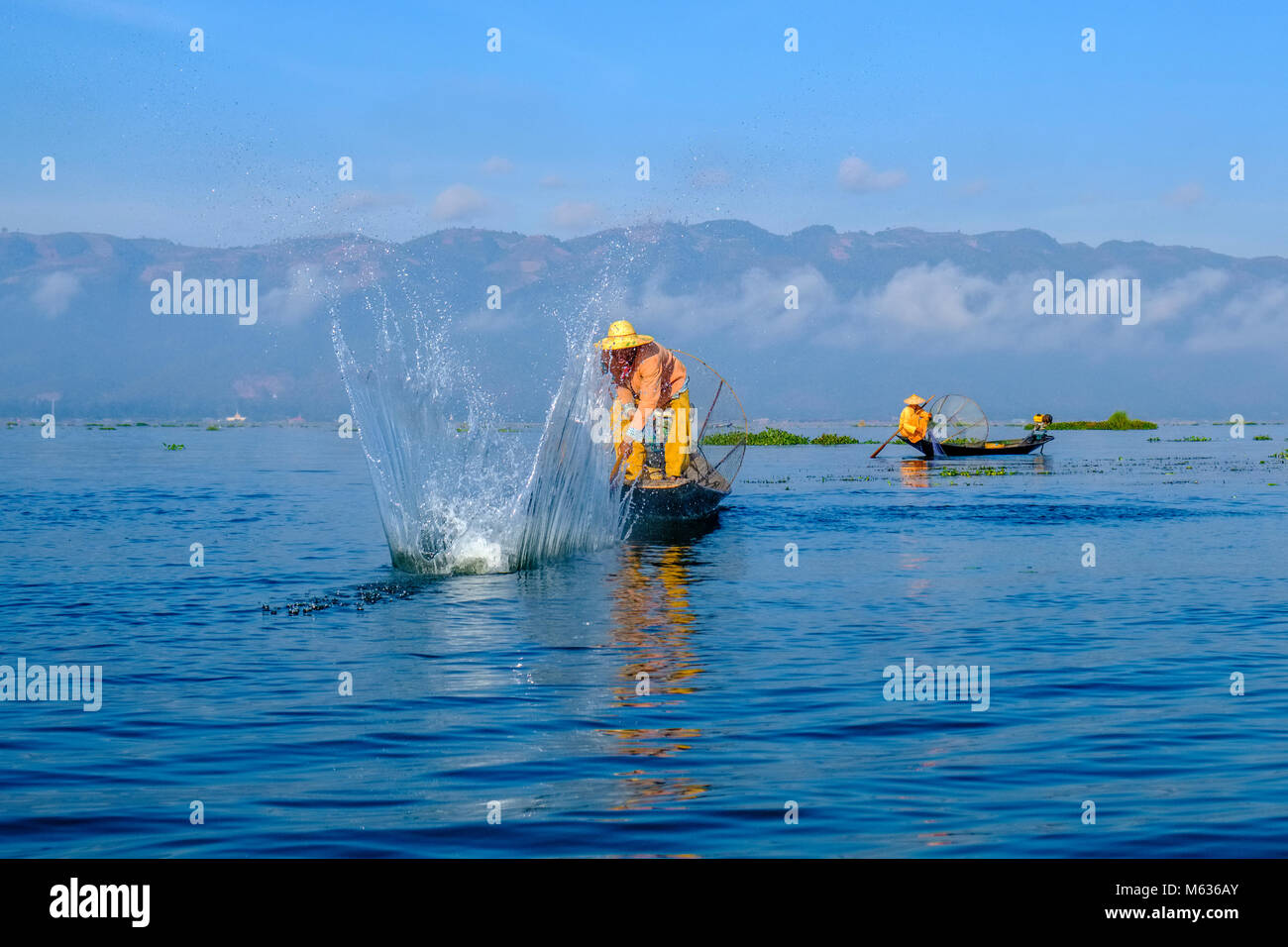 Two fishermen, standing on their boats, are fishing the traditional way ...
