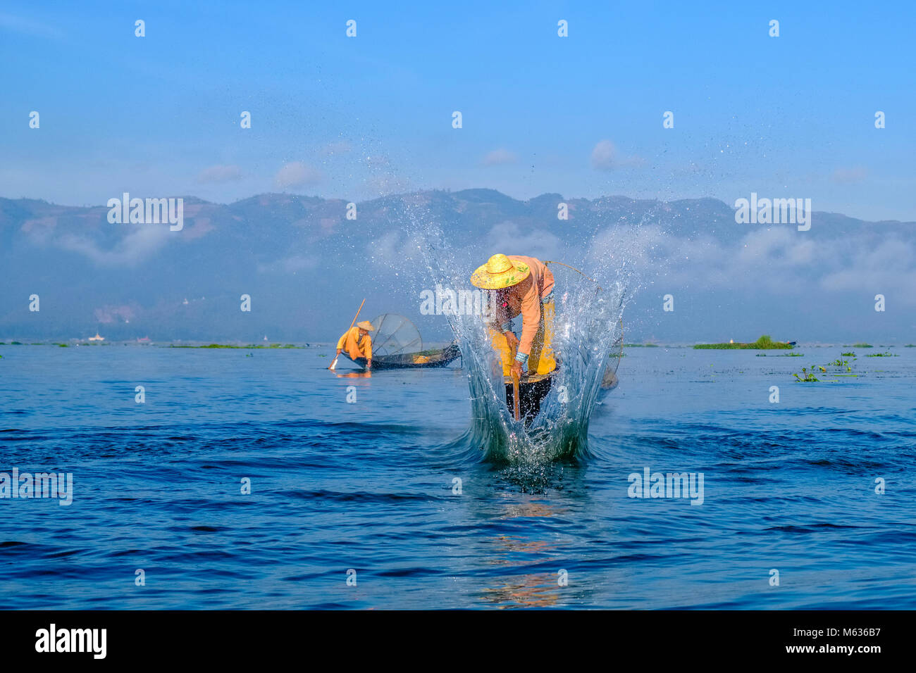 Two fishermen, standing on their boats, are fishing the traditional way ...