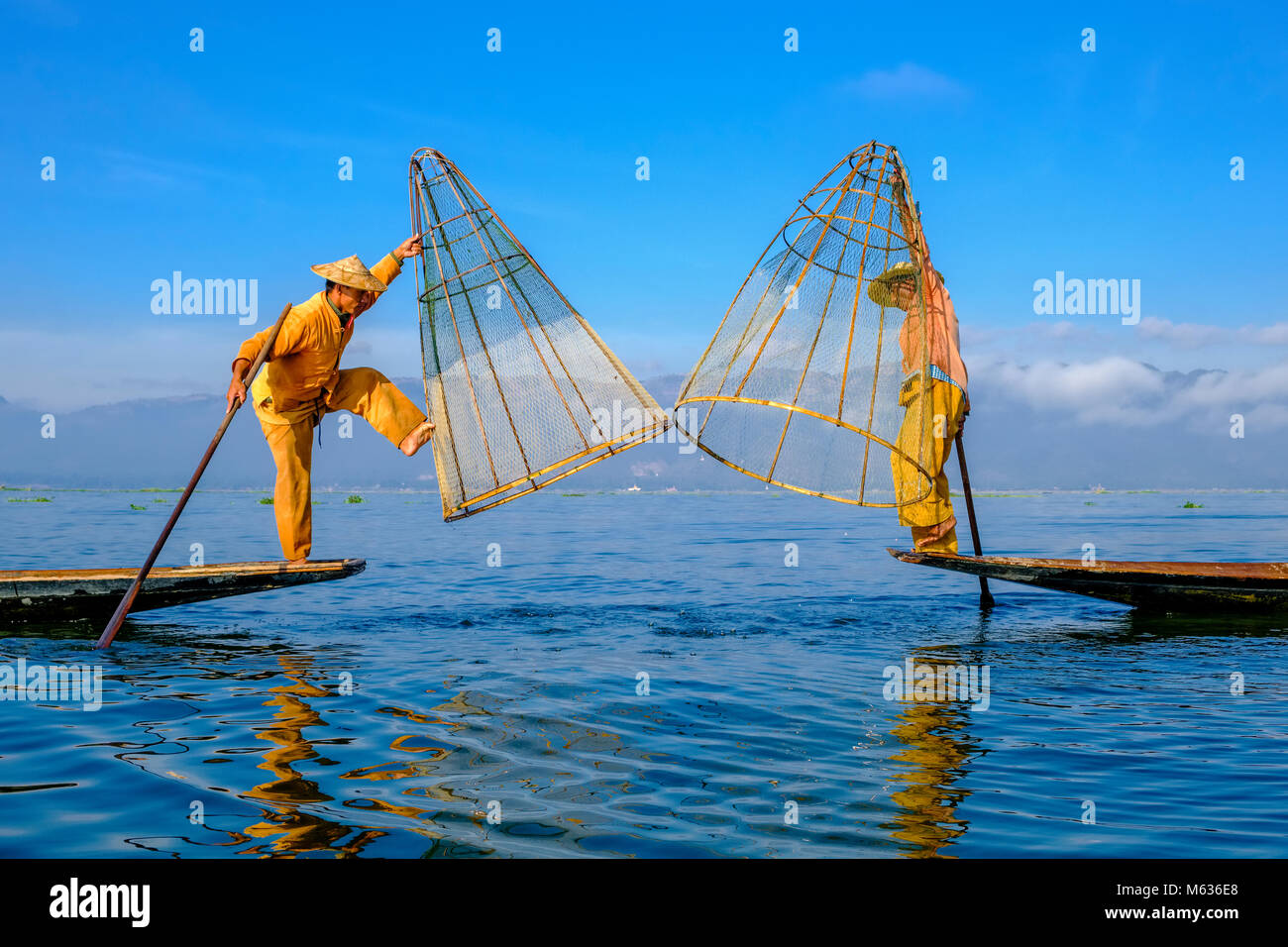 Two fishermen, standing on their boats, are fishing the traditional way ...
