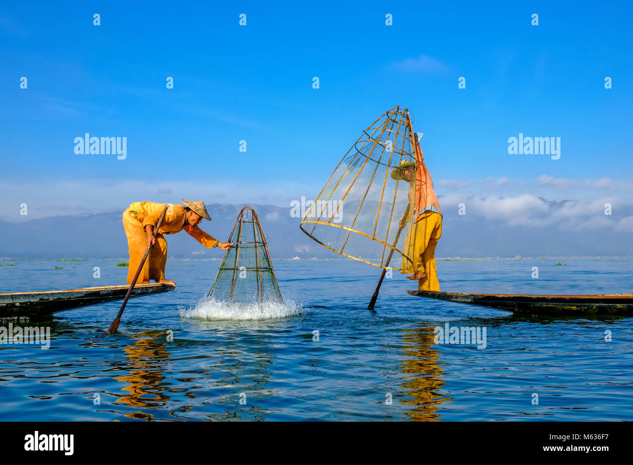 Two fishermen, standing on their boats, are fishing the traditional way ...
