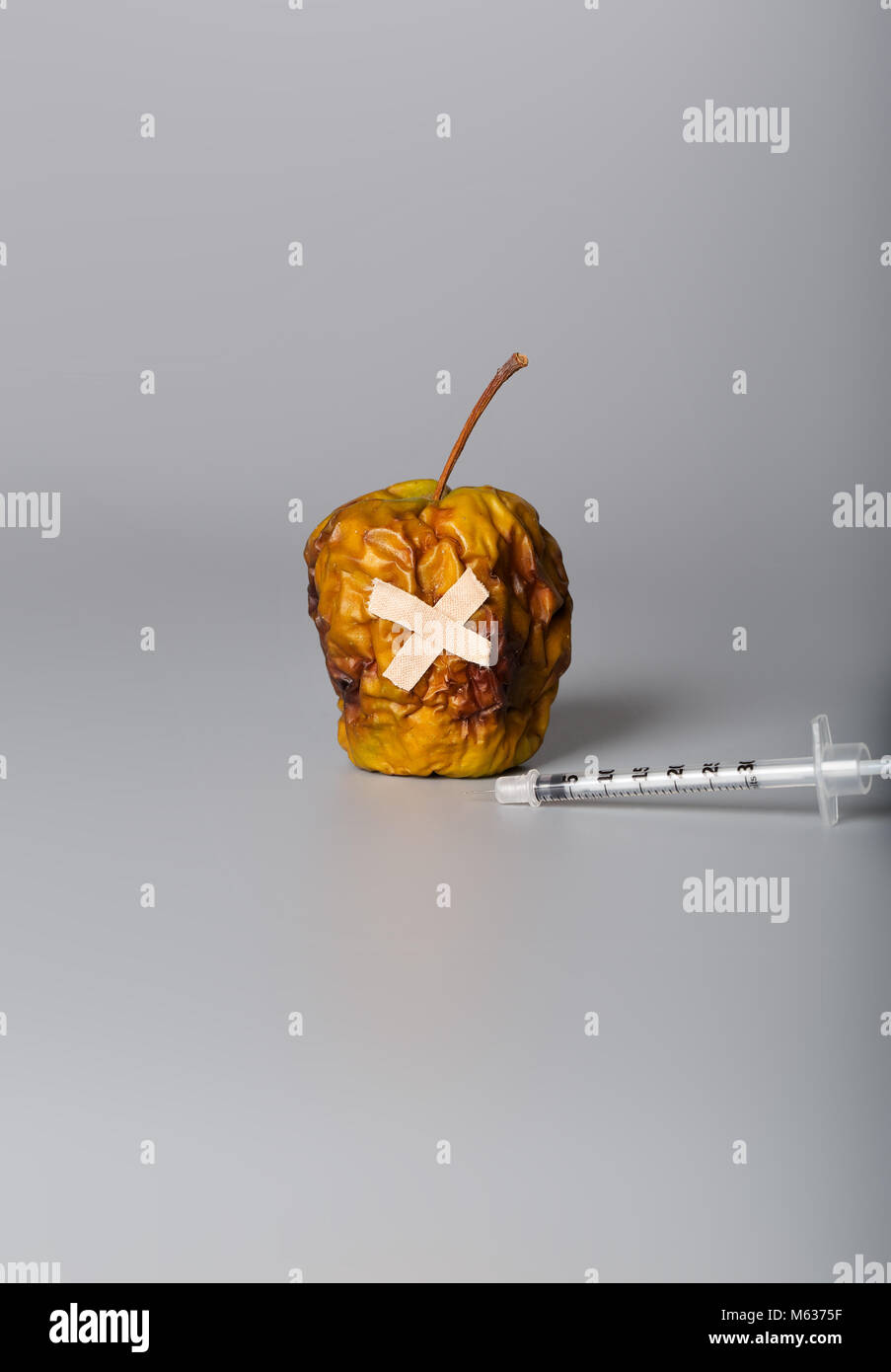 Shrivelled apple and insulin ultra thin syringe on a gray surface ...