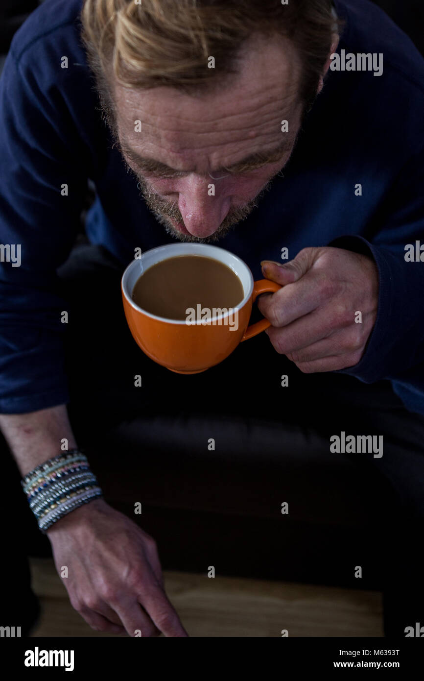 Close up of a white British man drinking coffee and having a biscuit ...