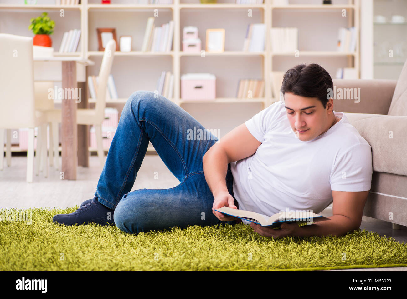 Man reading book at home on floor Stock Photo - Alamy