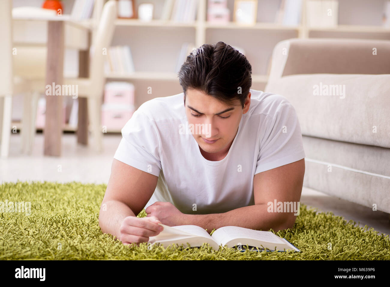 Man reading book at home on floor Stock Photo - Alamy