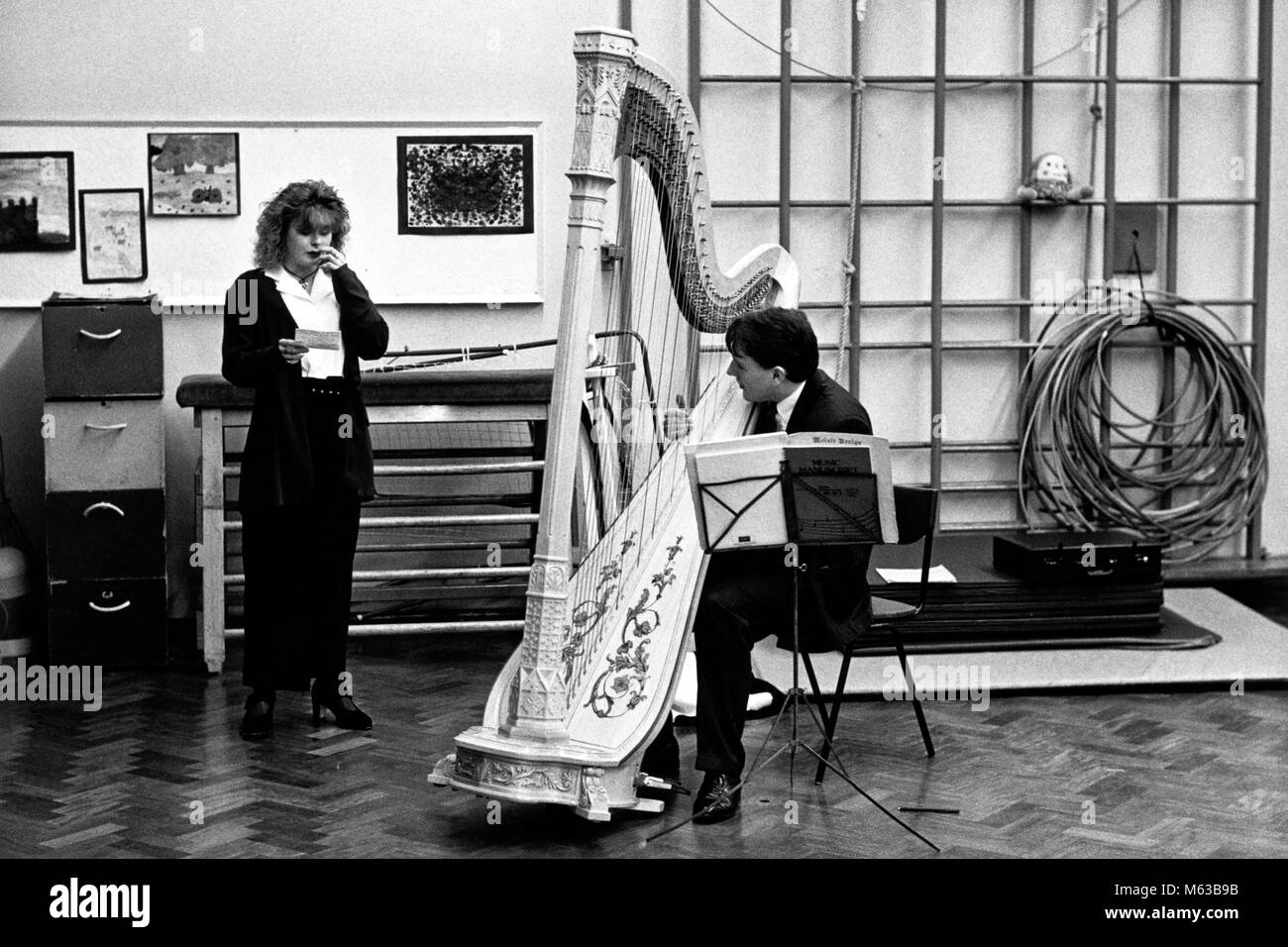 Male harpist practicing in school gym using concert harp at small ...