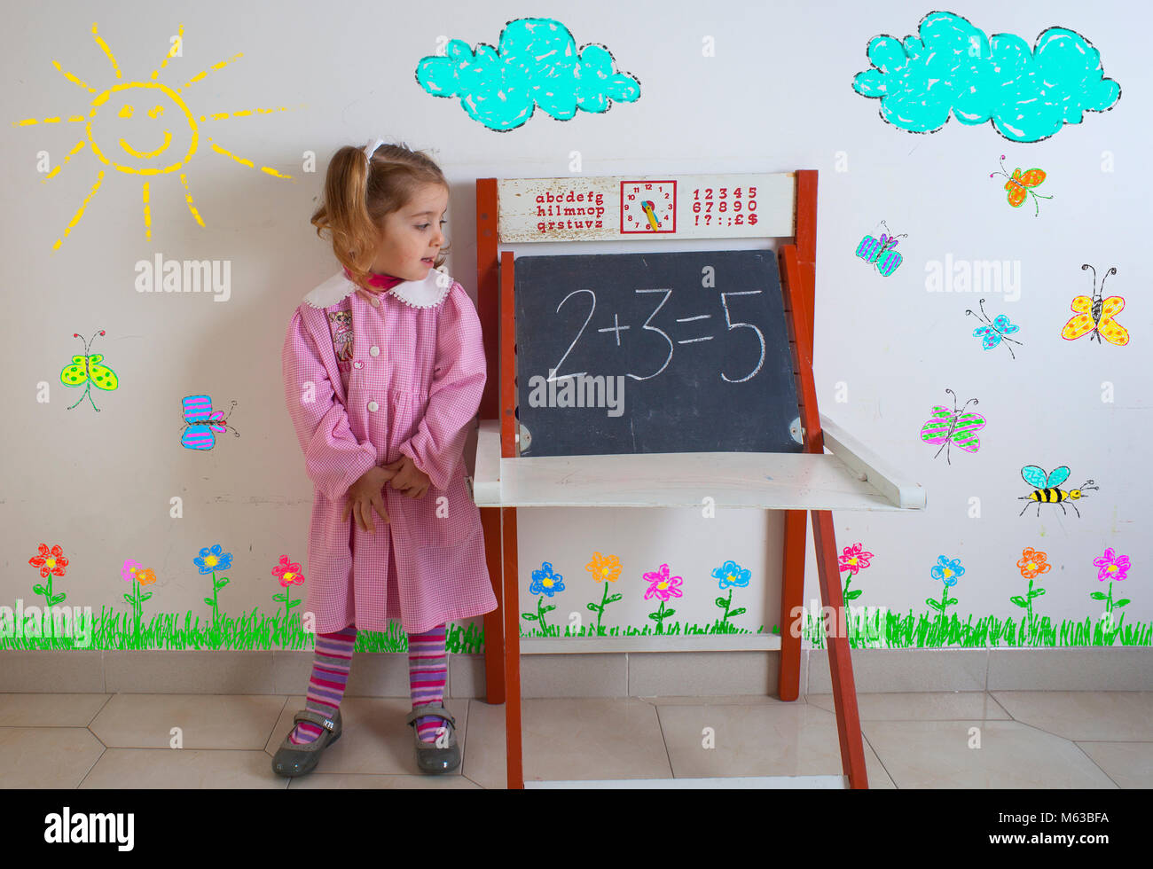 Tender child in smock next to the chalkboard Stock Photo - Alamy