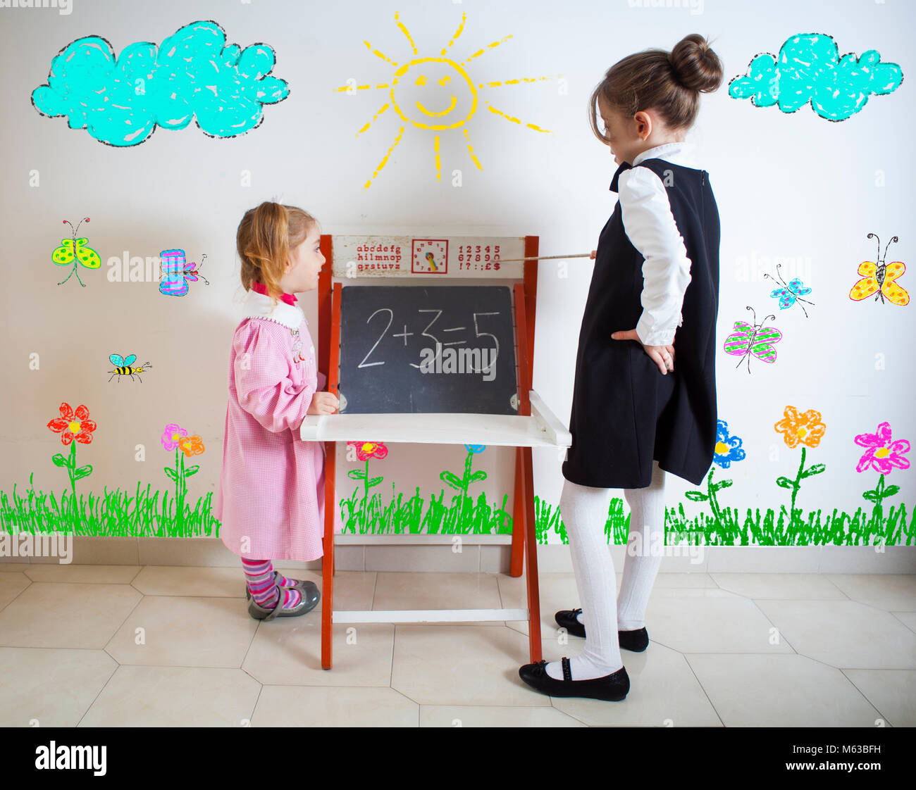 Little girl teaching mathematics to a younger child next to the ...