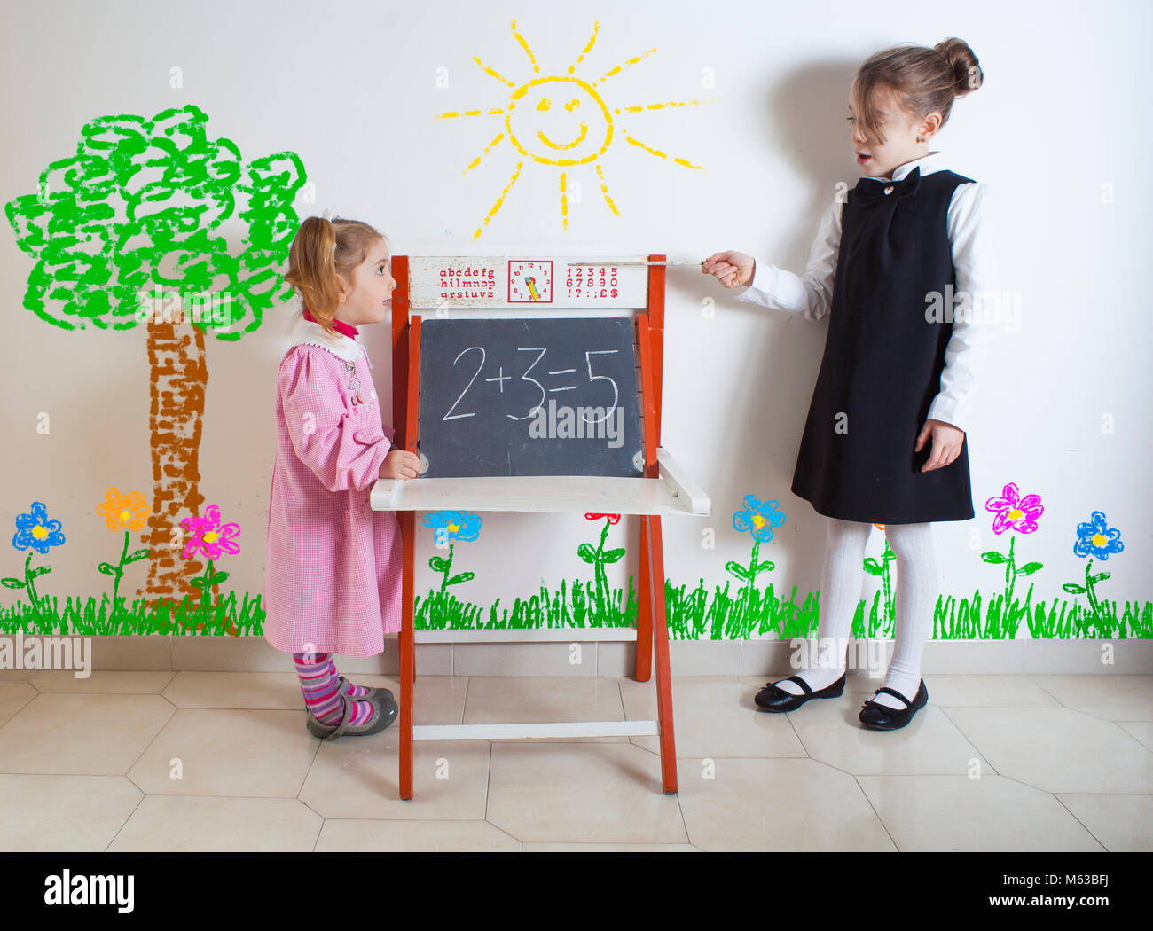 Little girl teaching mathematics to a younger child next to the ...
