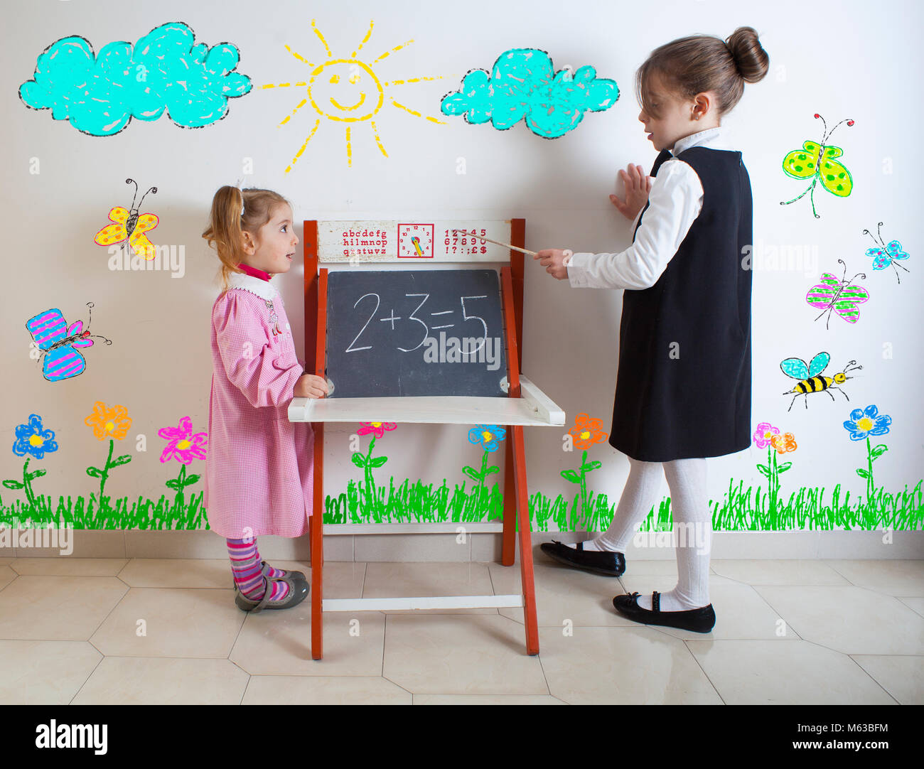 Little girl teaching mathematics to a younger child next to the ...