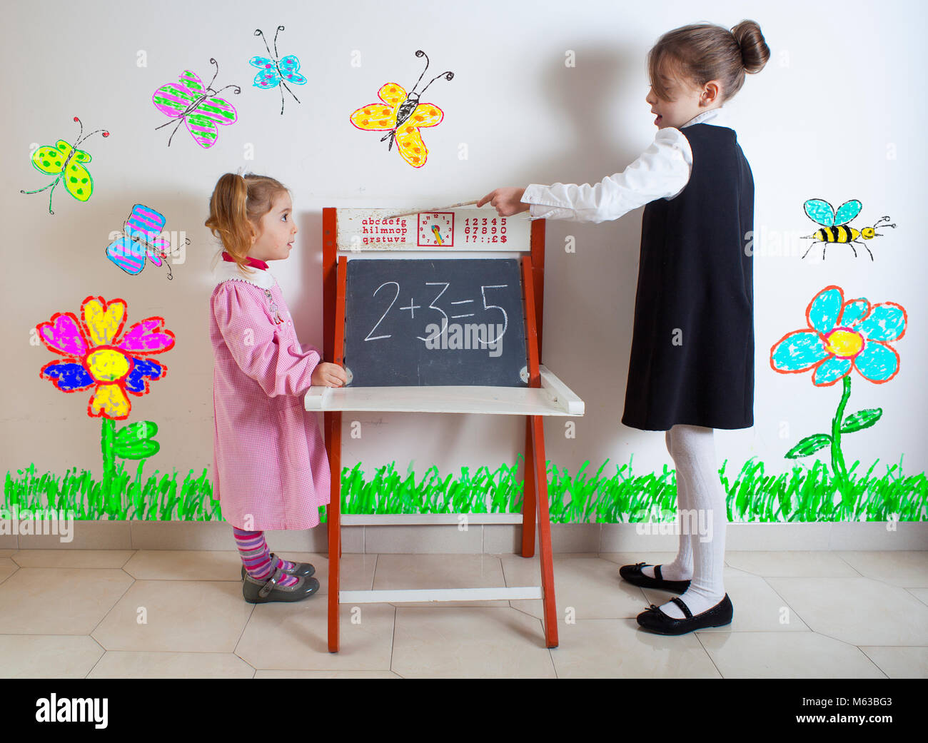 Little girl teaching mathematics to a younger child next to the ...
