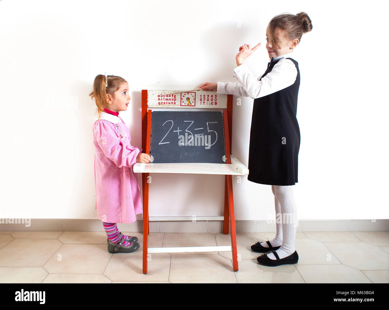 Little girl teaching mathematics to a younger child next to the ...