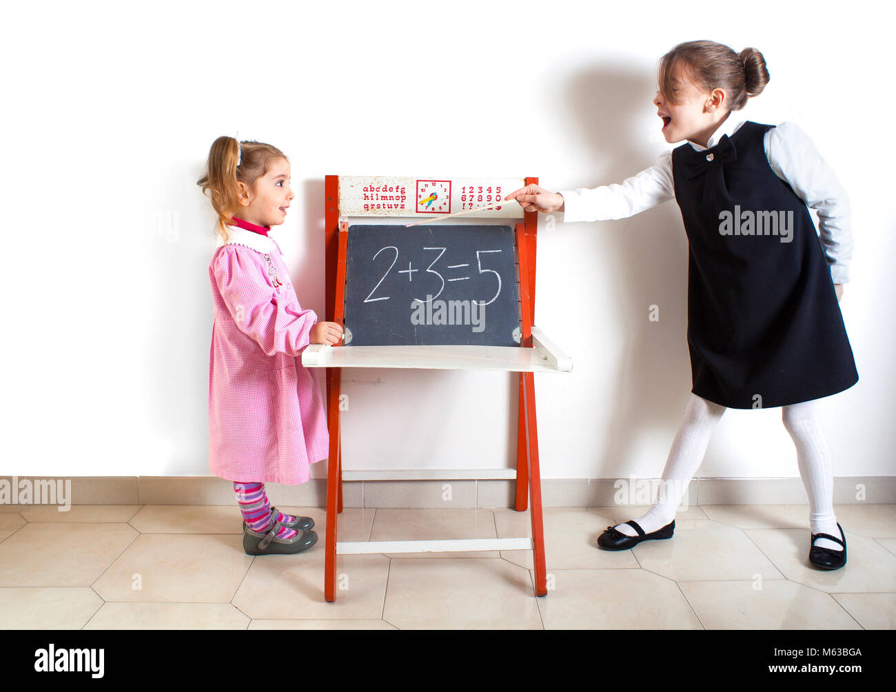 Little girl teaching mathematics to a younger child next to the ...