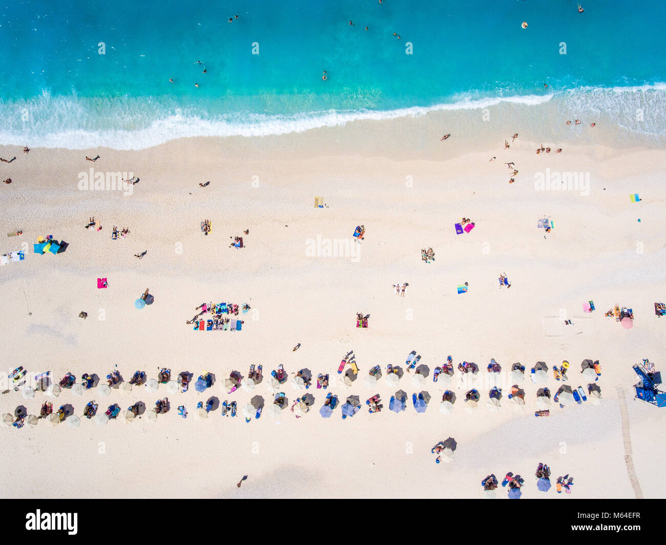 People bathing in the sun, swimming and playing games on the beach ...