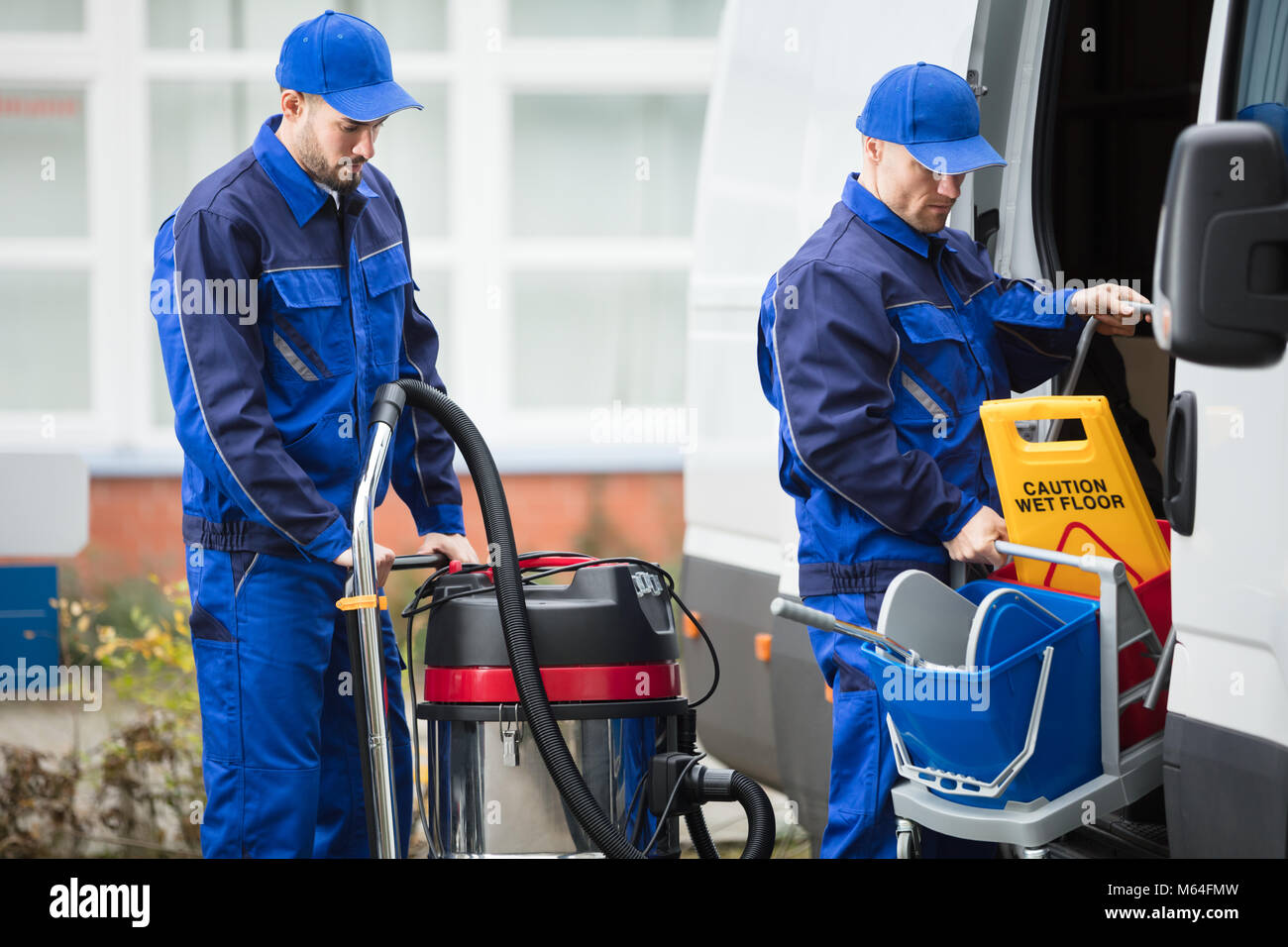 Two Young Male Janitor In Blue Uniform Unloading Cleaning Equipment ...