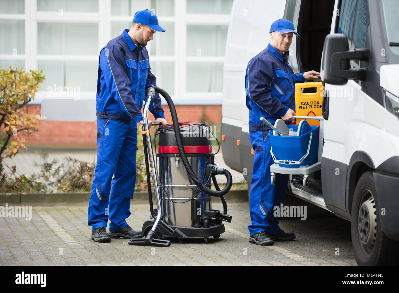 Two Young Male Janitor In Blue Uniform Unloading Cleaning Equipment ...